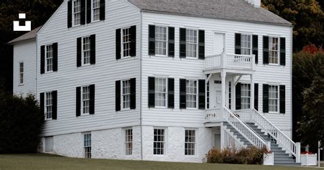 Une Grande Maison Blanche Assise Au Sommet Dun Champ Verdoyant Photo