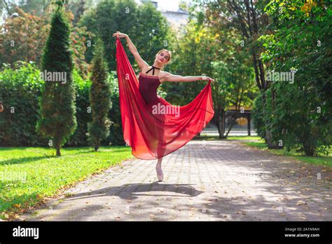 Woman Ballerina In Red Ballet Dress Dancing In Pointe Shoes In Autumn