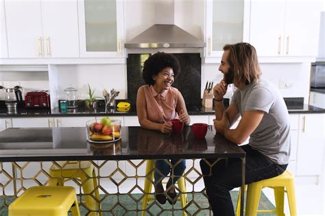 Premium Photo Happy Diverse Couple Sitting In Kitchen Drinking Coffee