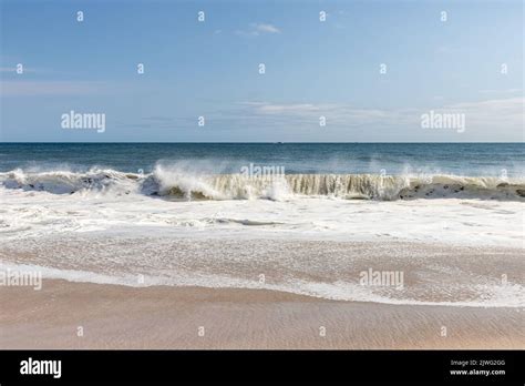 Ocean Waves Coming Towards The Sand Which Is Covered With Footprints