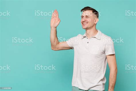 즐거운 젊은 남자 캐주얼 옷을 옆으로 흔들며와 인사와 함께 파란색 청록색 배경에 고립 된 통지로 사람들은 진심으로 감정 라이프 스타일 개념입니다 복사 공간을 모의 합니다 T