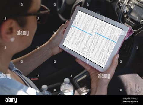 Biracial Female Programmer Sitting In Car Using Tablet With Coding On