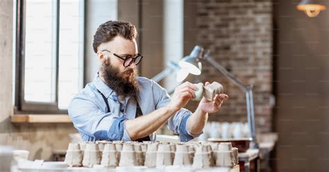 도자기 가게의 작업장에서 세라믹 공작물로 작업하는 잘생긴 수염 난 남자 사진 Unsplash의 제조 이미지