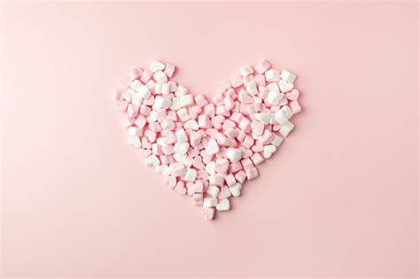 하트 모양의 핑크 마시멜로가 복사 공간이 있는 분홍색 테이블에 쌓여 있습니다 빈티지 스타일의 발렌타인 컨셉에 사랑 테마달콤한