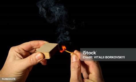 검은 배경에 불타는 성냥을 들고 손이 있습니다 나무 성냥이 매크로의 손에 타오른다 상자에 매치에 불을 붙입니다 경기에서 연기를 피우십시오 플래시 개념에 대한 스톡 사진 및