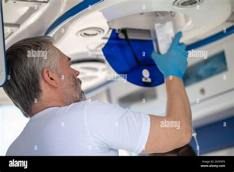 Experienced Paramedic Preparing For Administering Intravenous Infusion