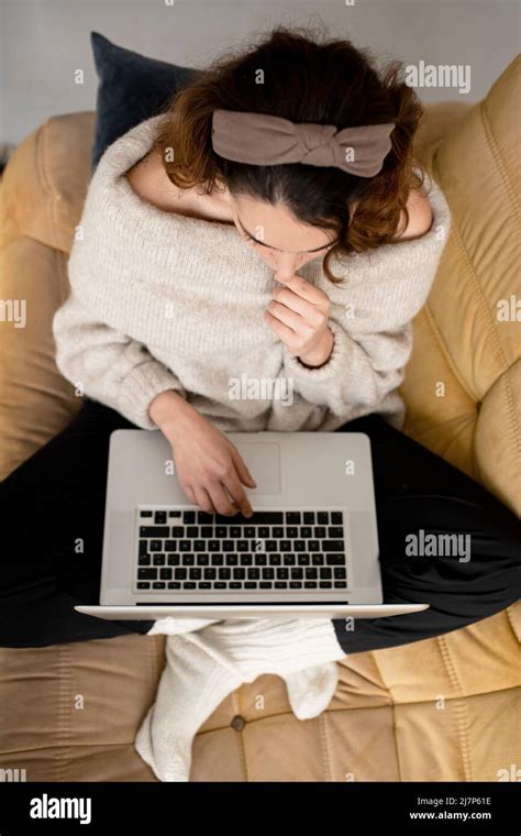 Top View Of Young Woman Cross Legged Sitting On Sofa Working On Laptop