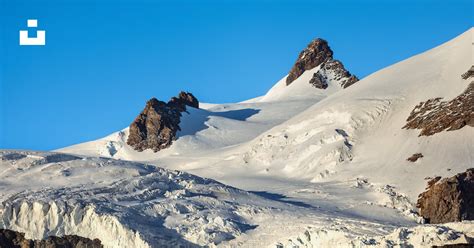 Une Grande Montagne Couverte De Neige Sous Un Ciel Bleu Photo Photo