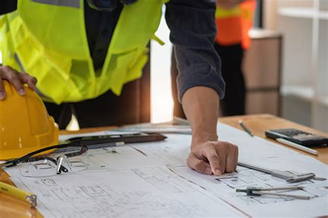 아시아 엔지니어들은 비용 견적을 문서화하고 주택 및 건물의 건축 및 엔지니어링 설계를 위한 평면도를 작성하기 위해 브레인스토밍 및 측정합니다 가리키기에 대한 스톡 사진 및