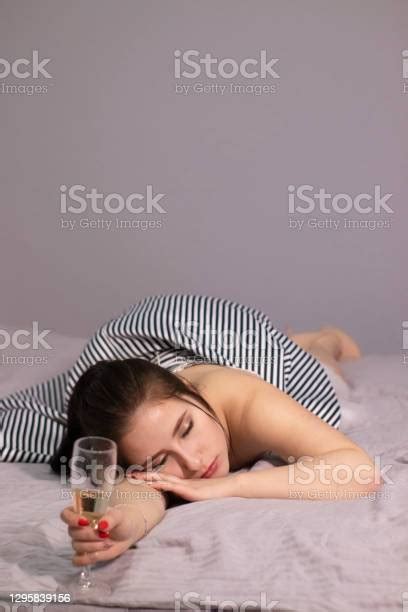 회색 침실의 침대에 샴페인 한 잔과 저녁 칵테일 드레스에 슬픈 매력적인 갈색 머리 여자 외로운 파티 외로움 드레스에 대한 스톡