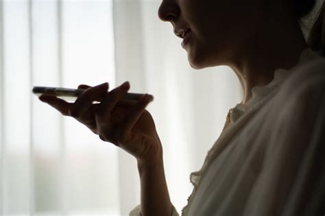 휴대 전화에 개인 비서와 이야기 하는 여자의 실루엣 휴대 전화에 음성 인식과 메시지를 기록 20 29세에 대한 스톡 사진 및