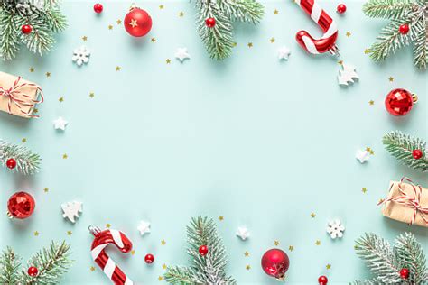 파스텔 블루 배경에 눈 덮인 전나무 가지 빨간 장식 선물 상자 사탕 및 솔방울로 만든 크리스마스 프레임 플랫 레이 새해 복 많이 받으세요 그리고 겨울 방학 배경 상의
