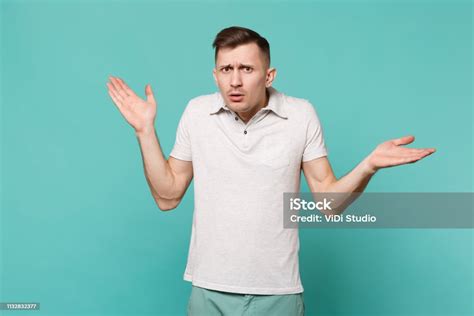 캐주얼 복장에 서 있는 젊은 남자의 초상화와 스튜디오에서 파란색 청록색 벽 배경에 고립 된 손을 확산 사람들은 진심으로 감정
