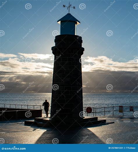 a man jogs around a lighthouse with him and the lighthouse is harp