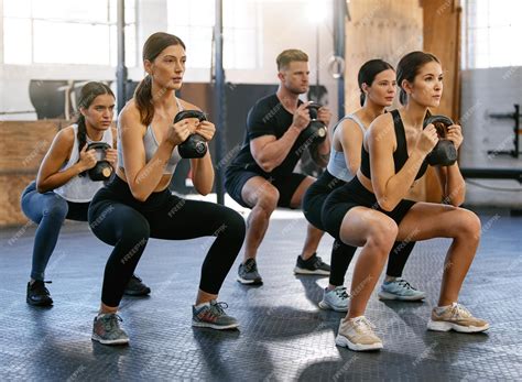 Premium Photo Weightlifting Group Kettlebell Squat And Fitness Exercise Class In Gym For
