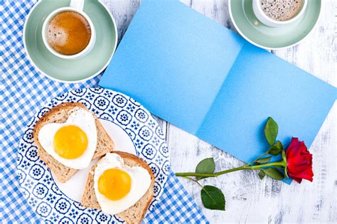 꽃 향기로운 커피와 연인 들의 낭만적인 아침에 대 한 심장모양의 토스트의 2 개의 컵 빨간 장미 편지 또는 메모 테이블에 발렌타인의 날 어머니의 날의 개념 플랫이 하다