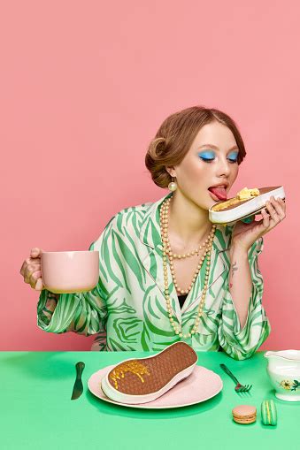 분홍색 스튜디오 배경에 버터를 바른 스니커즈 와플에서 꿀을 핥는 아름다운 어린 소녀 아침 식사와 커피 커피 마실 것에 대한 스톡 사진 및 기타 이미지 Istock