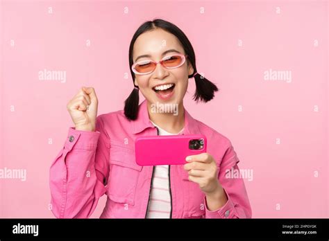 Happy Smiling Korean Girl Winning On Mobile Phone Looking At