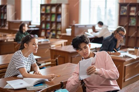 Premium Photo Teenage Guy Showing His Notes In Notepad To Classmate