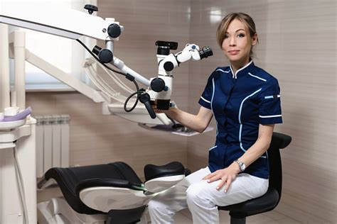 치과에서 현미경을 사용 하 여 치아 검사 연구 조사를 만드는 웃는 여성 의사 치과 의사는 현대 치과 사무실에서 환자를 치료 하