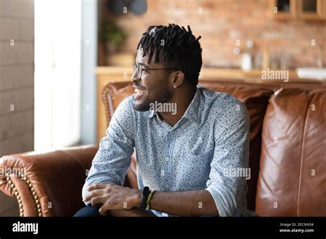 Close Up Dreamy Smiling African American Man Sitting On Couch Stock