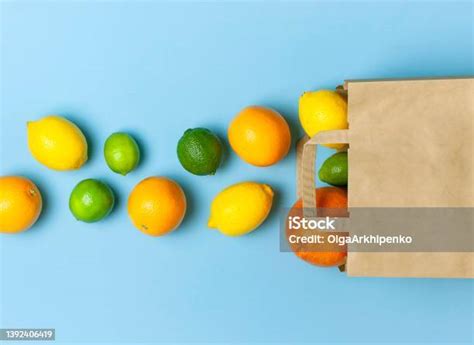 열대 과일로 창조적 인 배경 오렌지 레몬 라임 자몽은 파란색 배경에 종이 봉지에서 떨어집니다 플랫 레이 상단 뷰 복사 공간 식품
