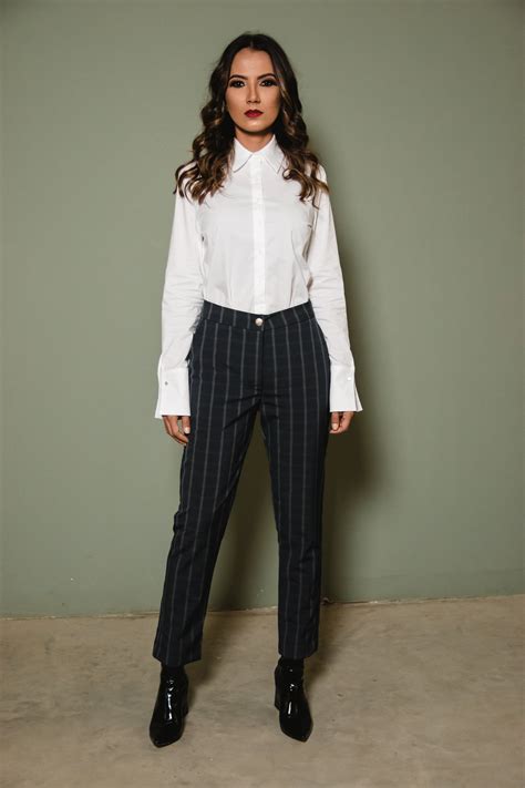 Woman Posing In White Dress Shirt And Black Pants Standing Against Gray