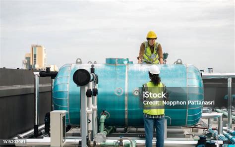 두 명의 전문 엔지니어 남성과 여성이 건물의 점검 및 유지 보수 파이프 라인 건설 꼭대기에서 일합니다 파이프 라인 건설 시스템에서 태블릿을 사용하는 안전 유니폼을 입은
