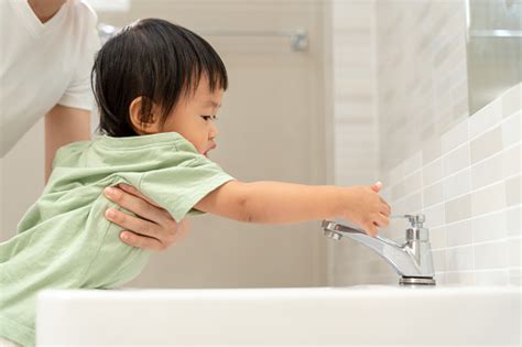 어린 아이의 손이 엄마와 함께 집 싱크대의 수도꼭지를 닫았습니다 어머니는 아이에게 물을 절약하도록 가르친다 세계 에너지를