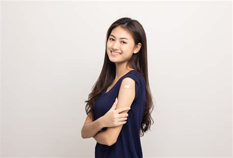 예방 접종 코로나바이러스백신 보호를 받고 있는 젊은 아름다운 아시아 여성 예방 접종을받은 후 붕대를 가진 팔을 보여주는 행복한