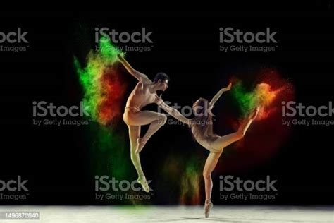 아름다운 젊은 남자와 여자 베이지색 바디수트를 입은 재능 있는 발레 댄서들이 검은 스튜디오 배경에 화려한 가루 폭발과 함께 춤을 춥니다 20 24세에 대한 스톡 사진 및