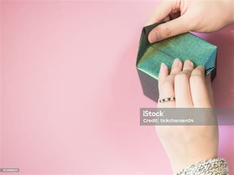 파스텔 핑크 배경에 녹색 빛나는 종이 선물 상자 크리스마스 생일이 나 새 해 축 하 행사에서 접는 아름다움 여자의 손 겨울에
