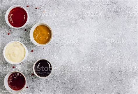 회색 배경에 다양한 딥 소스의 흰색 그릇 겨자 케첩 치즈 데리야키 크랜베리 소스 복사 공간이 있는 맨 위 뷰입니다 플랫 레이