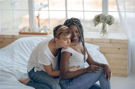 Short Haired Girl Hugging Her Dark Skinned Girlfriend From The Back And