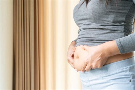 젊은 여자의 배꼽 여자는 그녀의 뚱뚱한 배 여자 다이어트 라이프 스타일 개념을 터치 프리미엄 사진