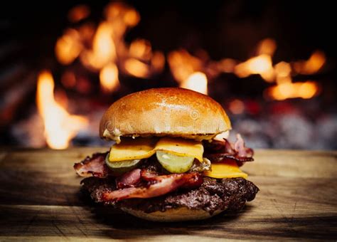 Smashed Cheeseburger On A Wooden Table In Front Of A Fireplace Stock