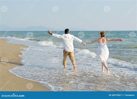 Pares Felices Que Se Ejecutan En La Playa Imagen De Archivo Imagen De