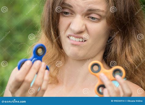 A Young Girl Looks At The Spinners In Her Hands And She Has A Fe Stock