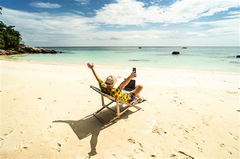 여름 모자를 쓴 남자 사업가 열대 해변에서 노트북과 휴대폰으로 일하는 디지털 유목민 프리랜서 색상 이미지에 대한 스톡 사진 및 기타 이미지 Istock