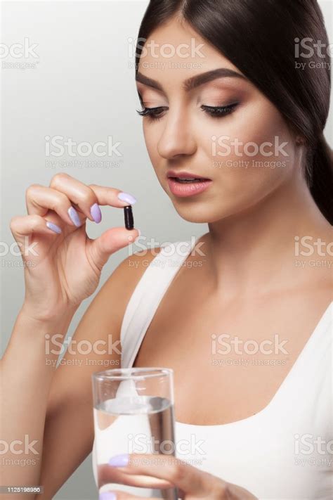 술 마약 젊은 아름 다운 소녀 약물을 복용 합니다 고통 스러운 상태입니다 물을 마셔 건강 보호 개념입니다 회색 배경 건강관리와