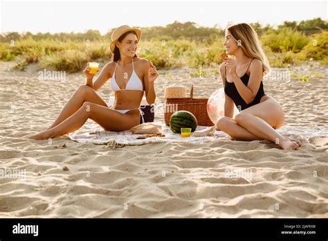 Young Two Women Wearing Swimsuit Smiling During Picnic On Beach Stock