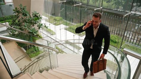 Happy Businessman Walking Up Stair And Calling Manager By Using Phone