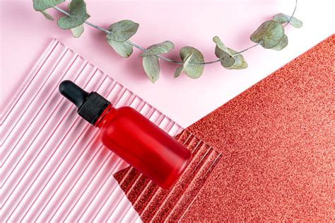 제품 사진 분홍색과 반짝이는 빨간색 배경에 빈 라벨이있는 얼굴 세럼 병 모형 뷰티 컨셉 얼굴 피부 케어 해양 재료로 노화 방지