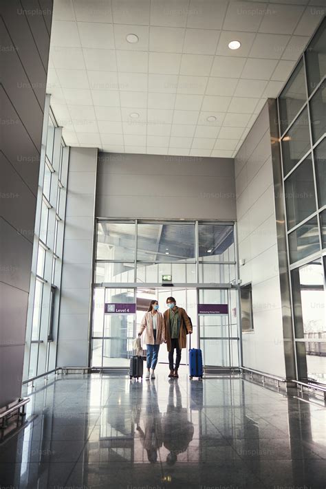 공항에서 여행 가방을 들고 보호용 안면 마스크를 착용한 세련된 남녀 사진 Unsplash의 여행 가방 이미지