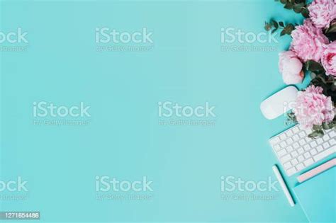 여성스러운 작업 공간 흰색 컴퓨터 키보드 마우스 모란 꽃 파란색 배경에 유칼립투스 꽃 맨 위 보기입니다 공간을 복사합니다 플랫