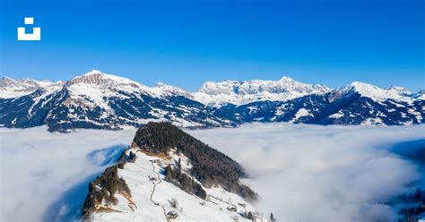 Une Montagne Couverte De Neige Et De Nuages Sous Un Ciel Bleu Photo