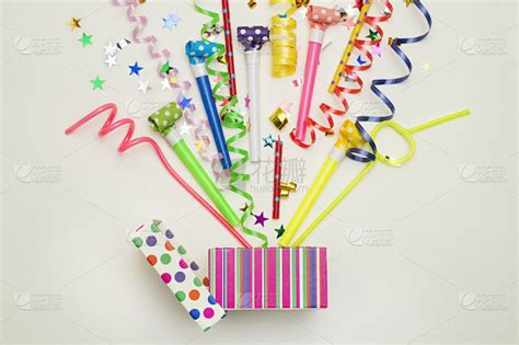 在绿色背景上装有各种派对彩纸、气球、彩带、噪音发生器和装饰的礼盒。丰富多彩的庆祝活动背景。