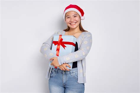 감사와 감사 산타 모자를 쓴 아름다운 젊은 아시아 여자가 흰색 스튜디오 배경에 격리된 선물 상자를 들고 있다 메리 크리스마스