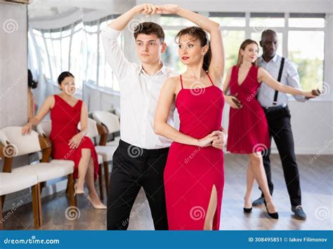 Hispanic Guy Practicing Samba With Woman In Red In Dance Class Stock