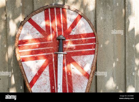 Medieval Shield With Red Patterns And Norman Sword In Front Of Rustic